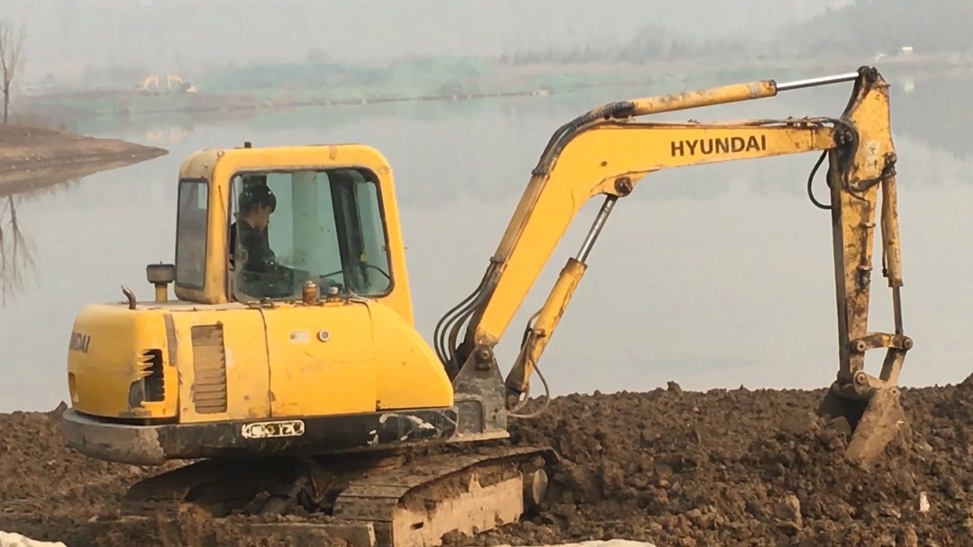 小型挖土机在湖边清理淤泥施工视频