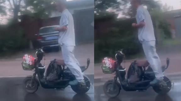 大爷脱把站后脚蹬处骑电动,双手不停捻着佛珠,原地跳跃活动身子