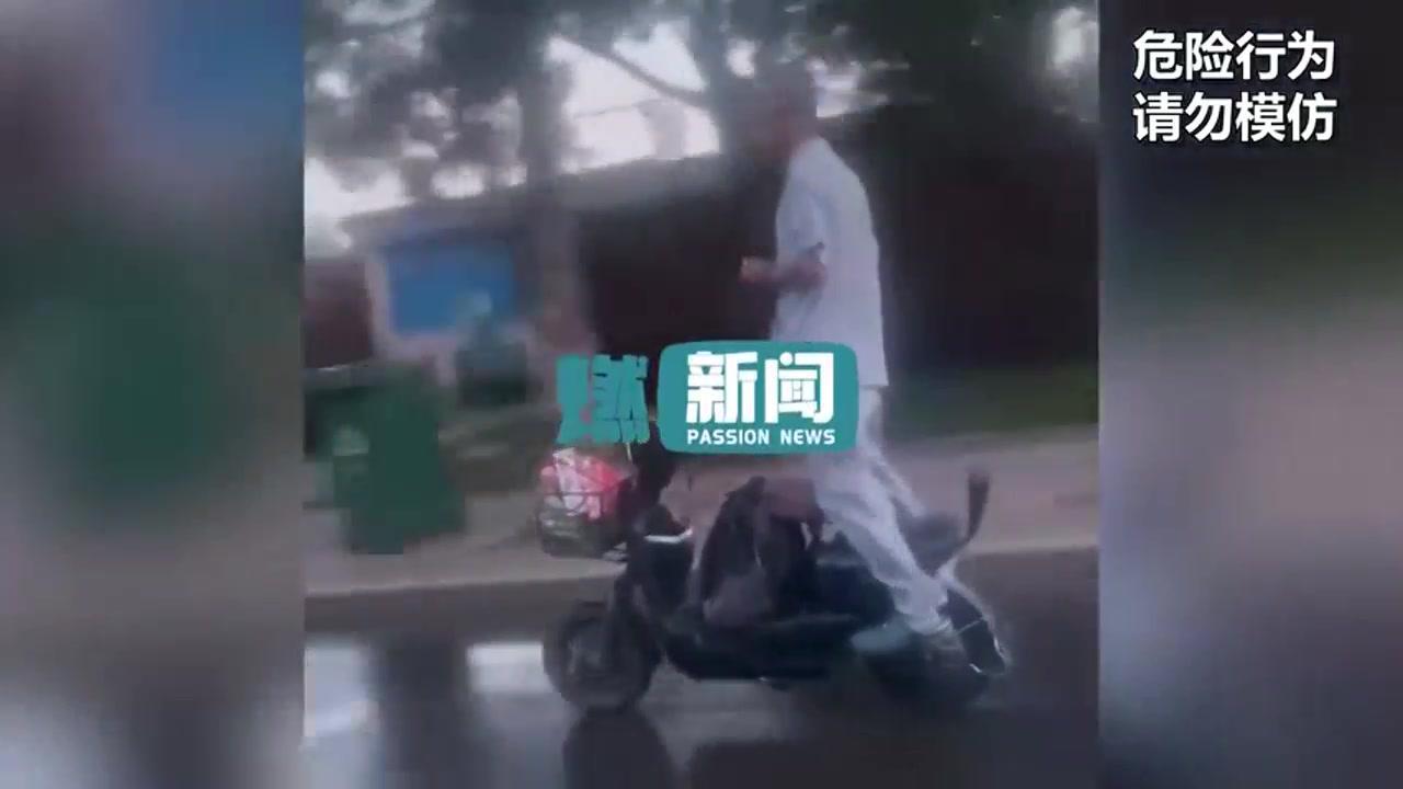 太危险!大爷站得笔直骑电动车双手还捻佛珠