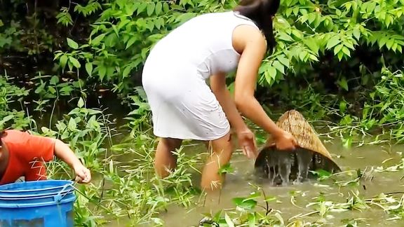 为了抓到大鱼,这位农家妇女每天在河中用簸箕捞鱼,很辛苦