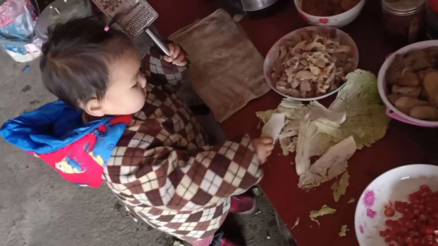 宝妈在切菜,一旁宝宝好奇也学着妈妈的模样拿起刀切菜