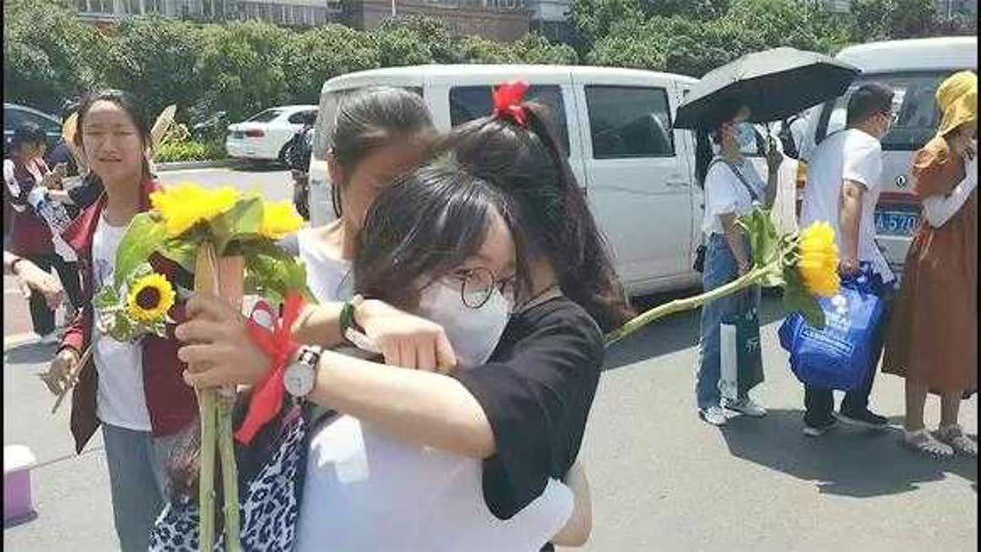 郑州一学校毕业生离校现场,每人一枝向日葵,校服被写满名字