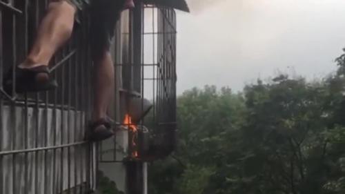 对面的邻居家着火,小伙爬窗拿灭火器救火,为你的正能量做法点赞