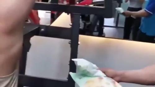 ...健身房里点了一份外卖,外卖小哥来了以后,给大哥示范健身器材的正确...