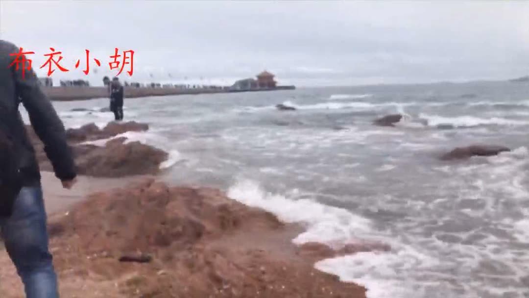 青岛栈桥,八大关海边游玩,小伙在沙滩上写字,海浪拍过来全没了