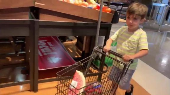 小男孩推着手推车帮妈妈到超市买东西