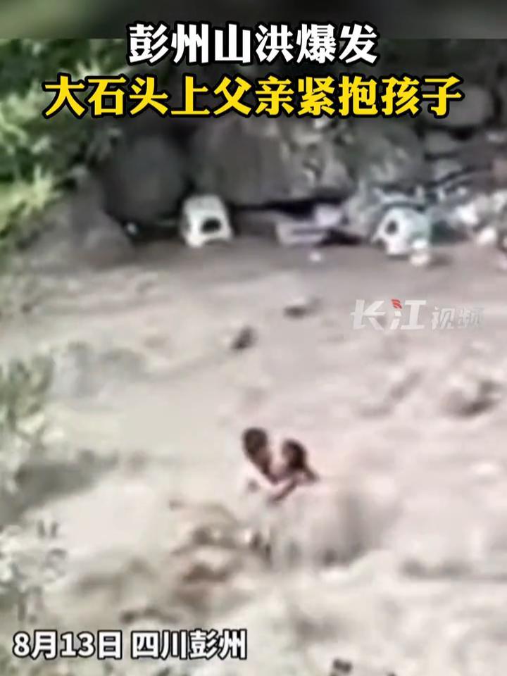 8月13日,四川彭州,彭州山洪爆发,大石头上父亲紧抱孩子。