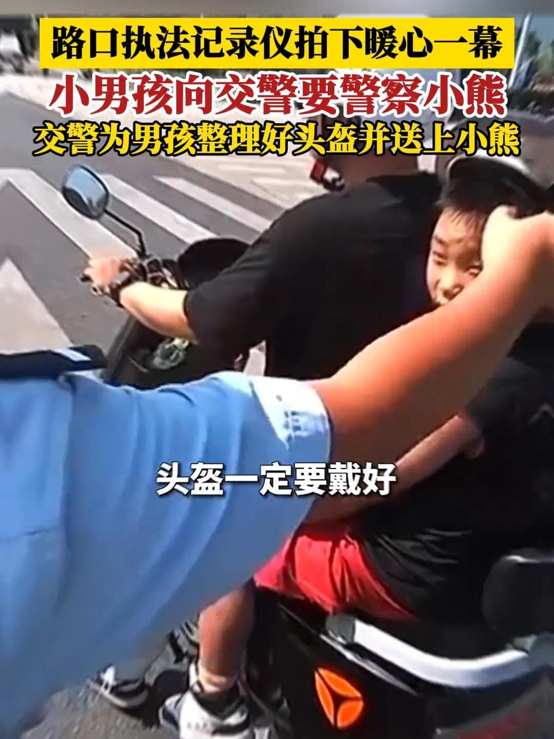 路口执法记录仪拍下暖心一幕,小男孩向交警要警察小熊,交警为男孩戴...