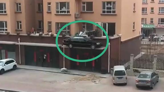 辽宁一奔驰车被停到居民楼屋檐 城管局:开发商为做宣传,已处理