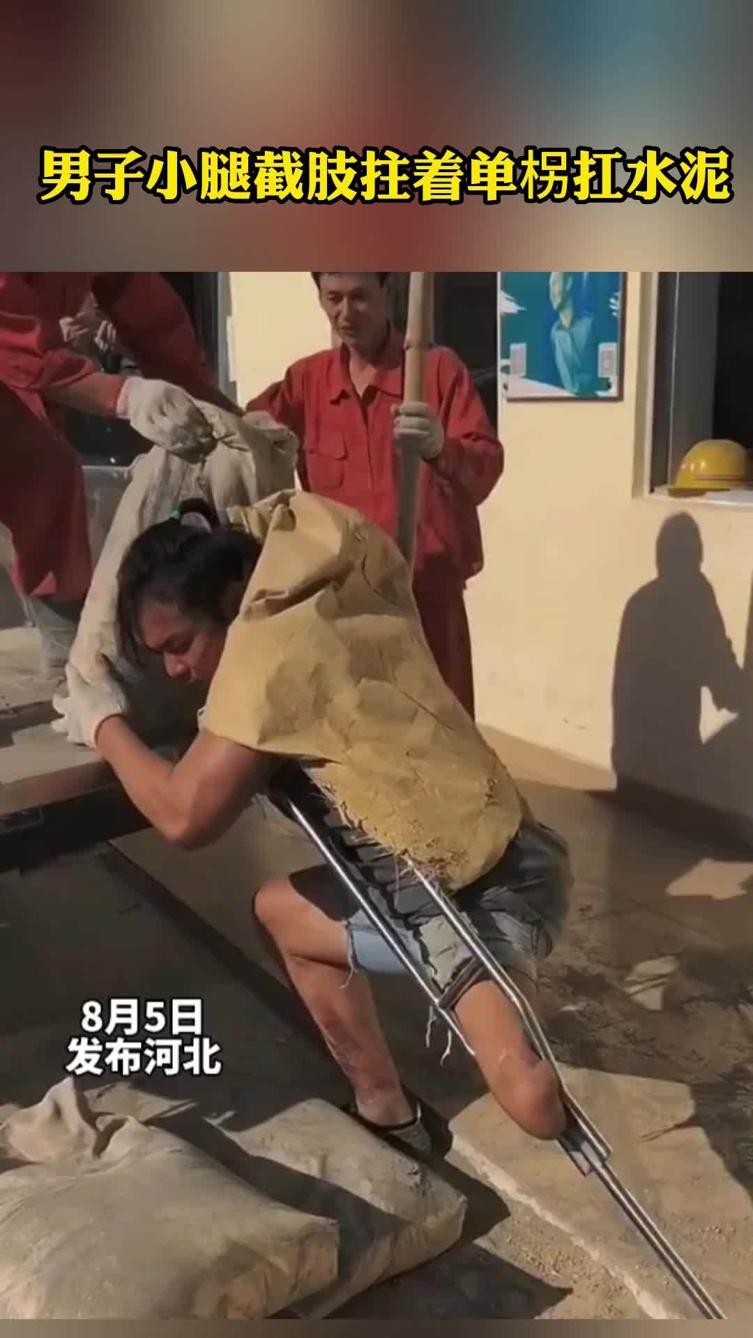 男子小腿截肢拄着单拐扛水泥