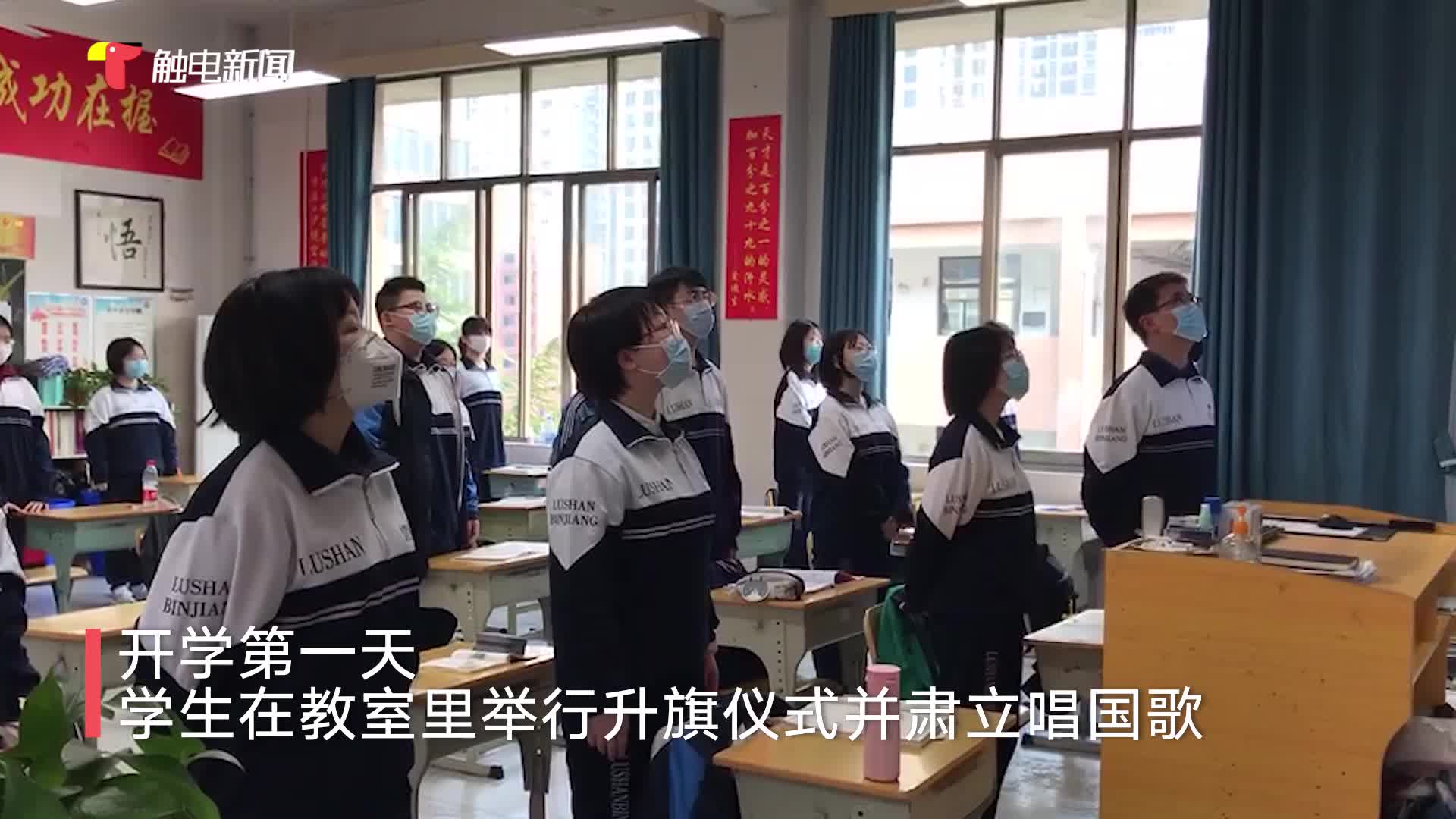 开学第一课,学生在教室举行升旗仪式,肃立奏唱国歌