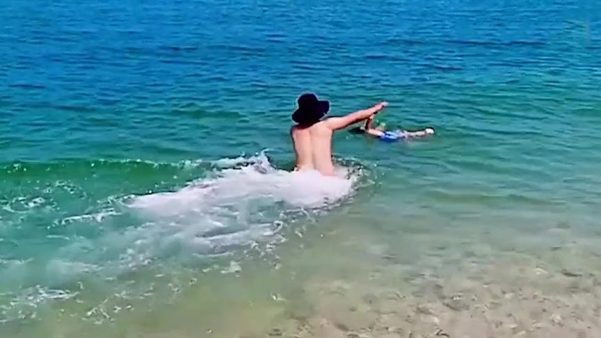 女子在岸边拍摄风景 无意间记录男子营救落水小孩全程