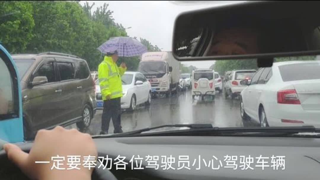 大雨天气,学校门口道路交通堵塞,交警同志在雨中指挥交通,可敬