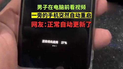 男子在电脑前看视频,一旁的手机突然自动重启,网友:正常自动更新了