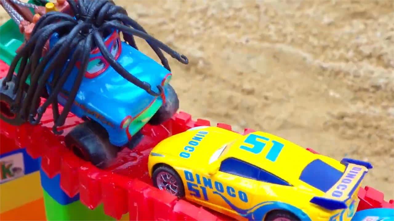 儿童喜欢的赛车总动员玩具车和工程车挖掘机在沙堆上搭建积木桥梁