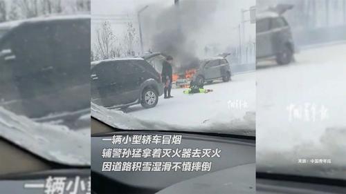 一辆小型轿车冒烟辅警拿着熄灭器去熄灭因道路积雪湿滑不慎摔倒