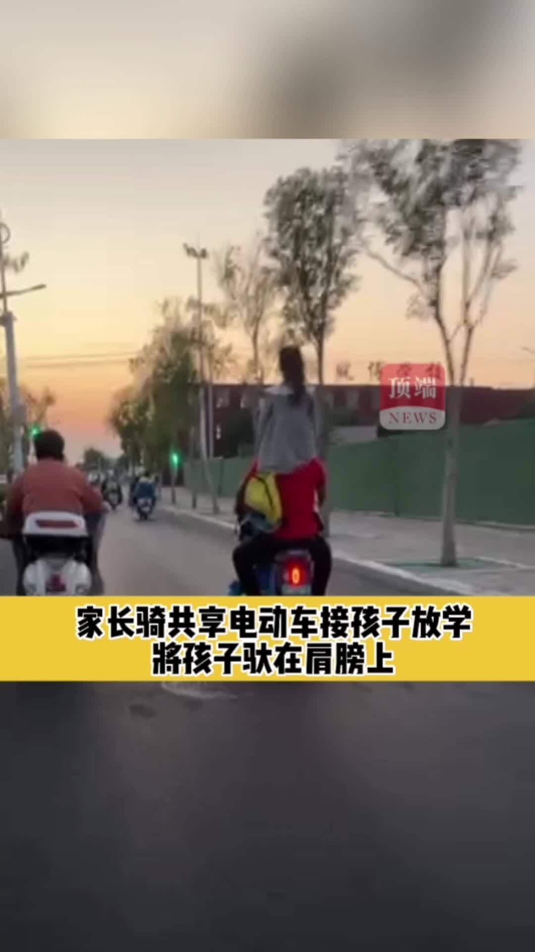 家长骑共享电动车接孩子放学将孩子驮在肩膀上 拍摄者:太危险了,前边...
