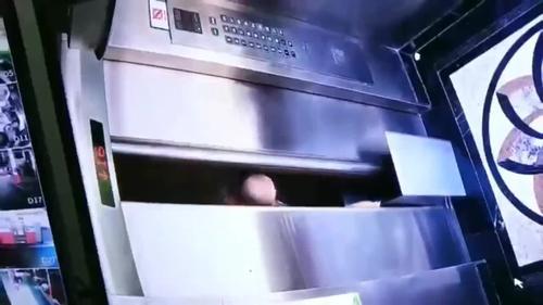 工人用铁皮挡电梯门,不料门被关上,电梯上升,弄坏电梯门