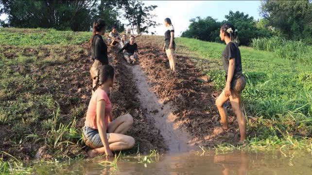 女孩制作土滑梯,从高处滑到河里,全程哈哈大笑
