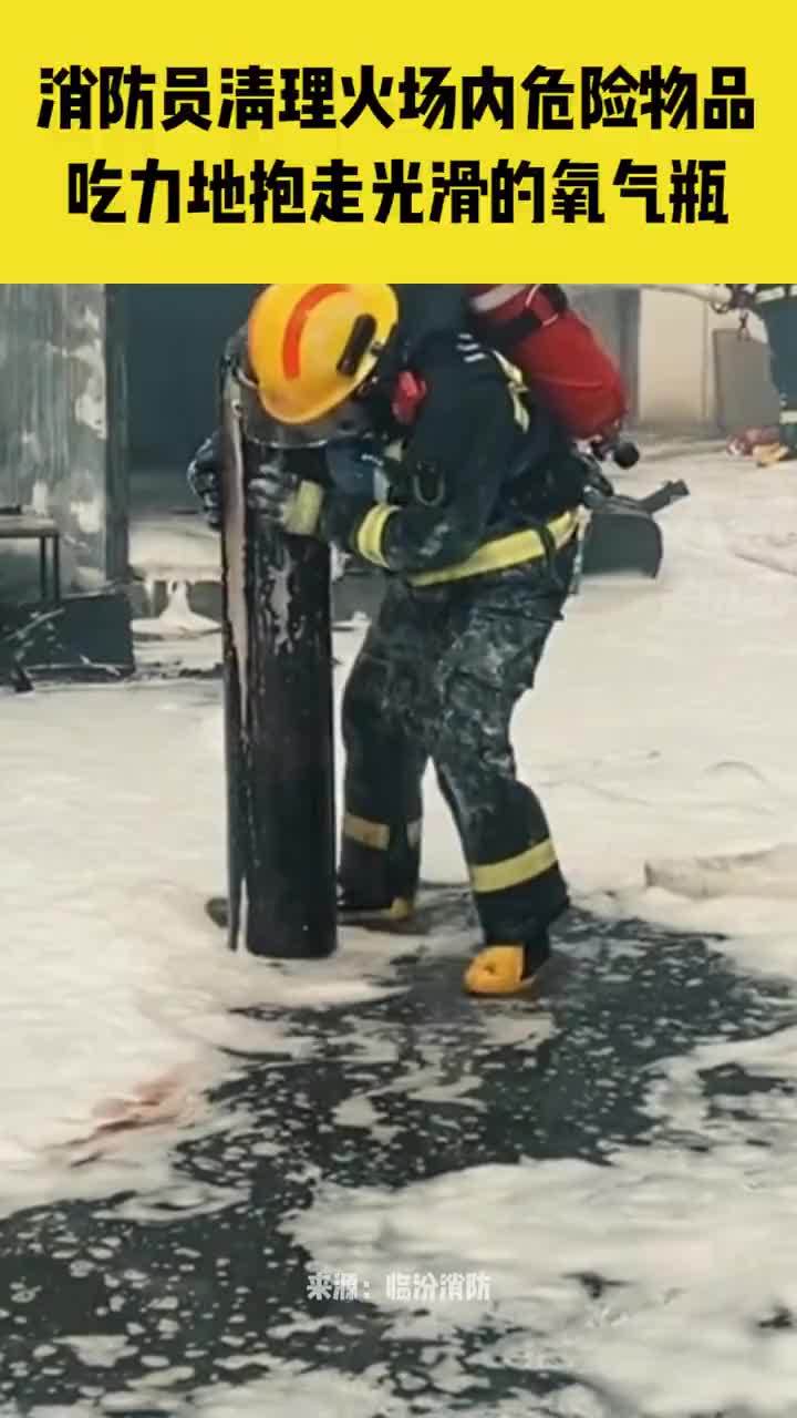 消防员清理火场内危险物品,吃力地抱走光滑的氧气瓶防止爆炸
