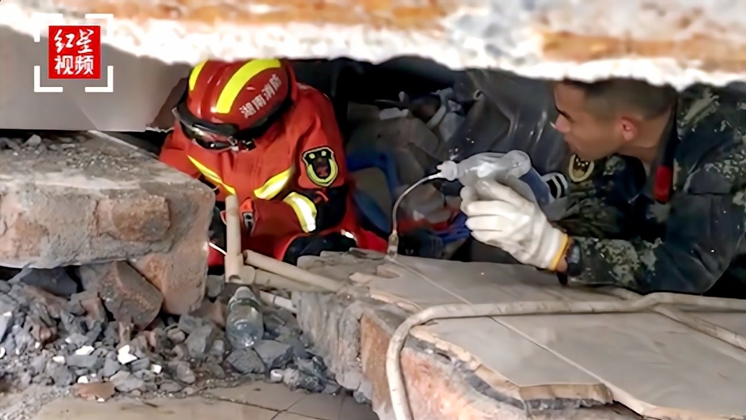 湖南郴州房屋坍塌救援现场:消防员坍塌楼体间给被困者喂水