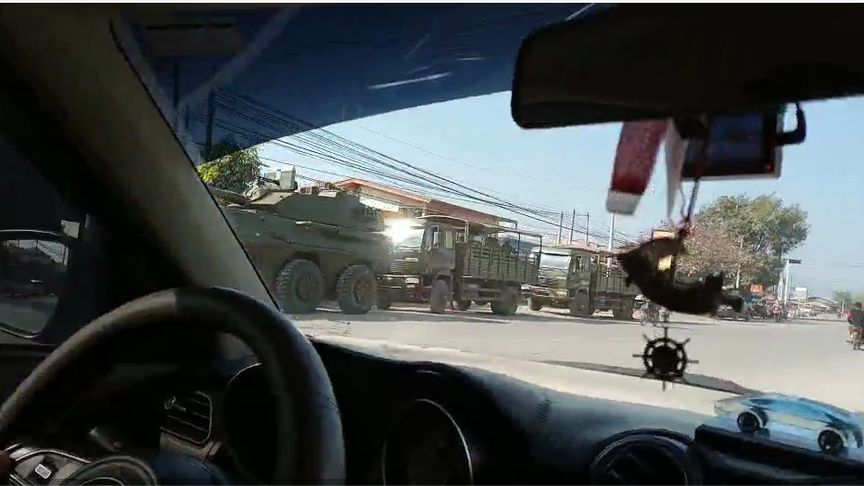 ...驾车上街实地拍摄,路边停着一排装甲车和军用卡车,路面行人车辆稀少