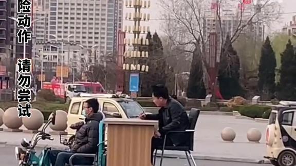 2月24日,德州一男子坐三轮运送桌椅不忘在车上办公。网友:...
