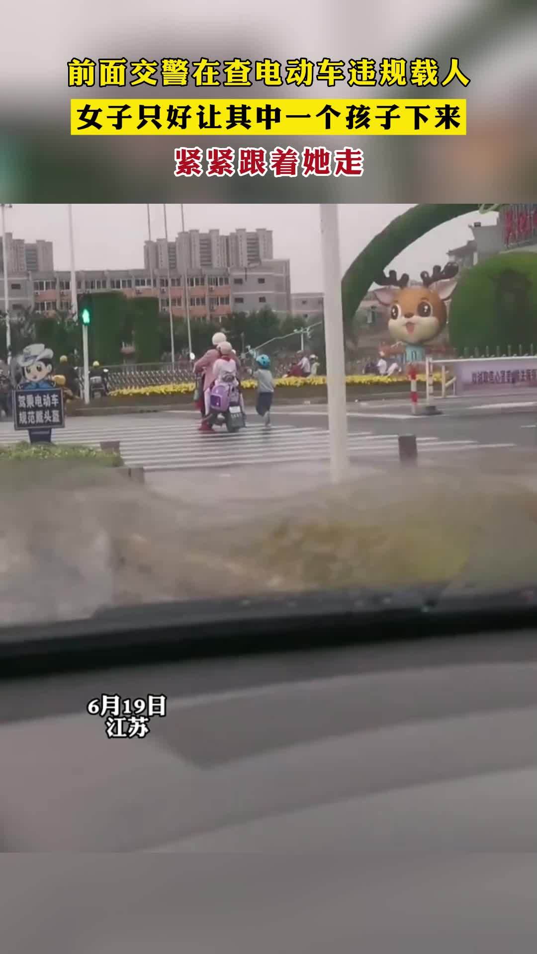 前面交警在查电动车违规载人,女子只好让其中一个孩子下来