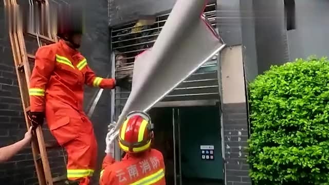云南一男童被卷帘门卷在半空 消防全力救助
