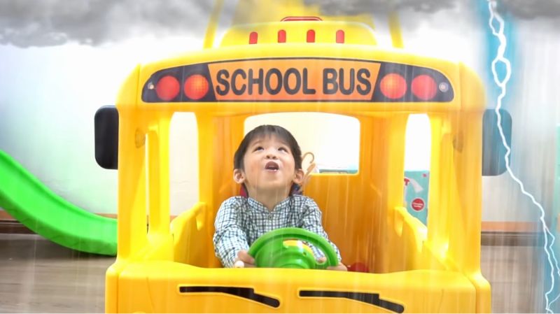 宝宝吃着棒棒糖开着小巴士,撑起了小雨伞