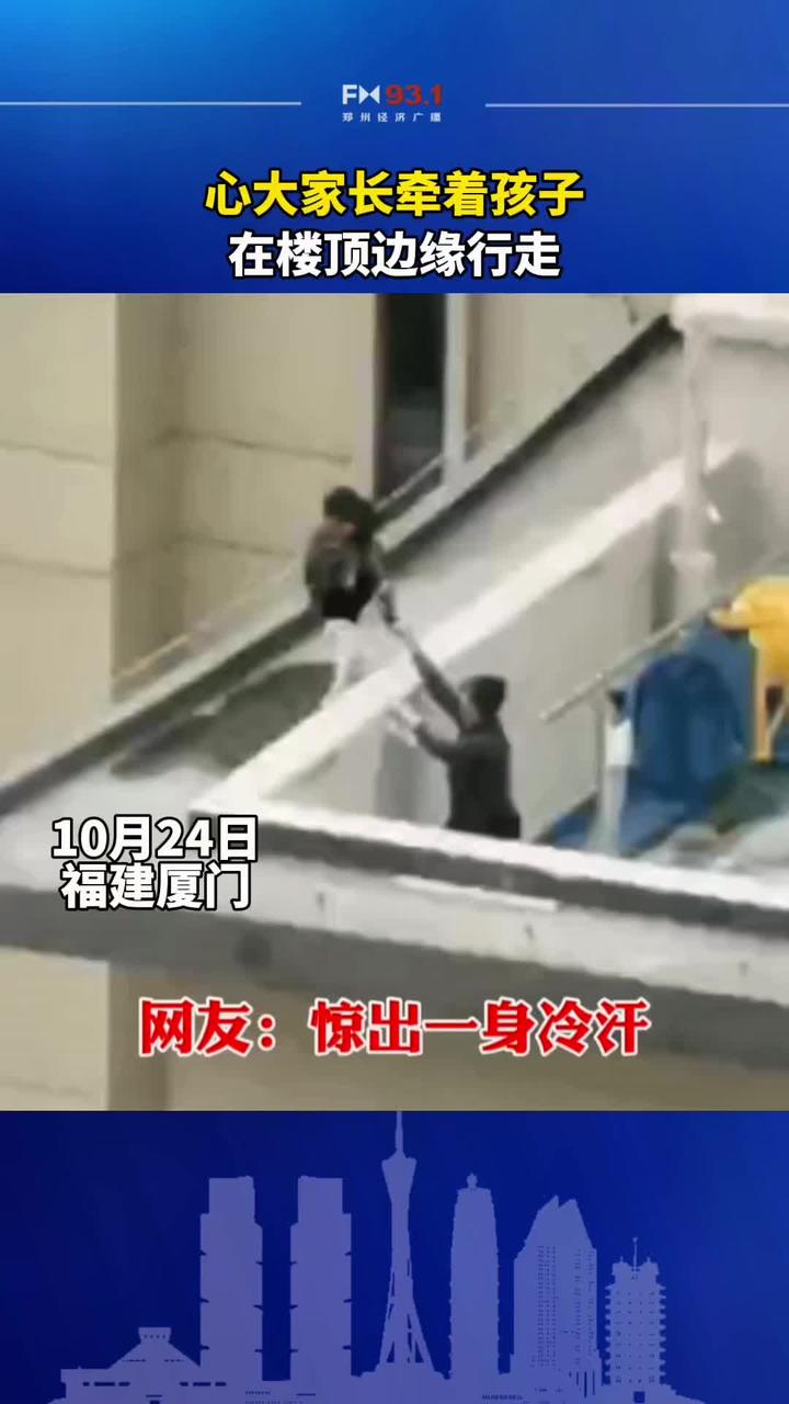 福建厦门一家长牵着孩子手竟在楼顶边缘行走。危险动作请勿模仿!
