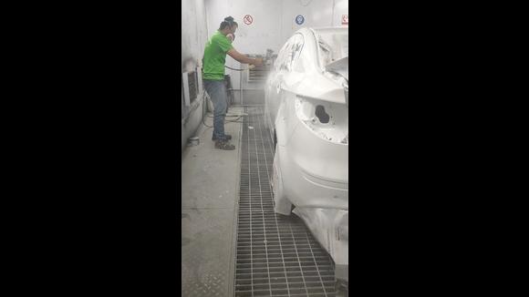 正在烤漆房里,给汽车喷漆。