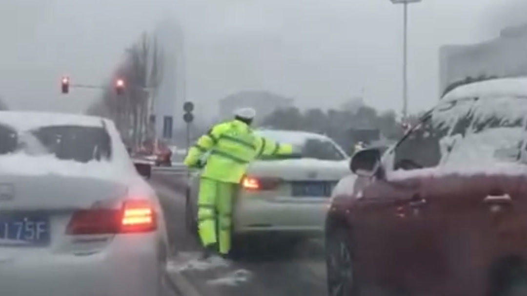 路上轿车玻璃积雪 暖心交警徒手捊去
