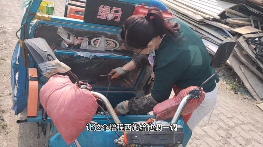 这辆小三轮车安装了一台增程器,美女给他固定在了坐箱里面了