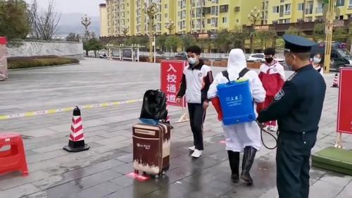 孩子们开学了,保安叔叔们站在学校门口,给到来的学生和行李消毒!