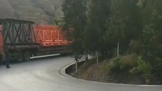 半挂车拖着桥梁支架在转弯的时候翻了,挂车陷在了路边出不来