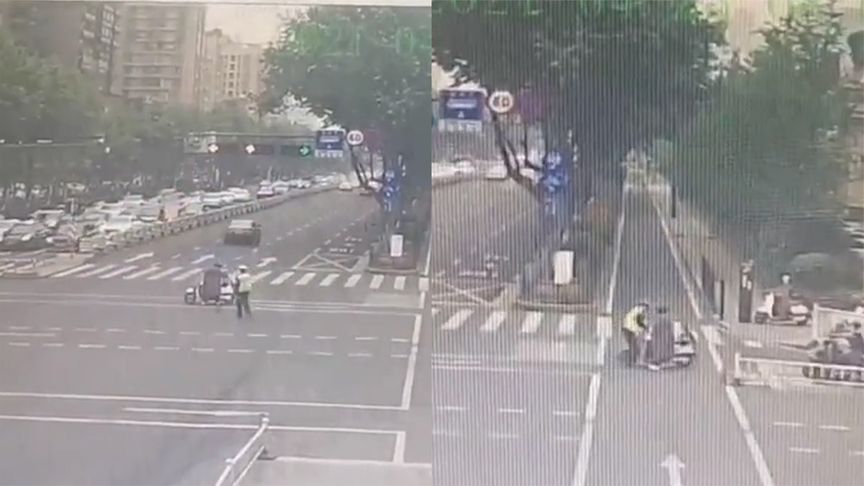 女子骑电动车过马路,雨衣却卷入车轮停在路中,交警紧急上前处理