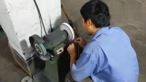 敬业的车间小伙用打磨机磨麻花钻钻头