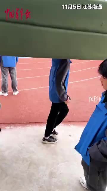 学校运动会结束,三名高一男生摆出三角队形,头顶垫子运回器材室。