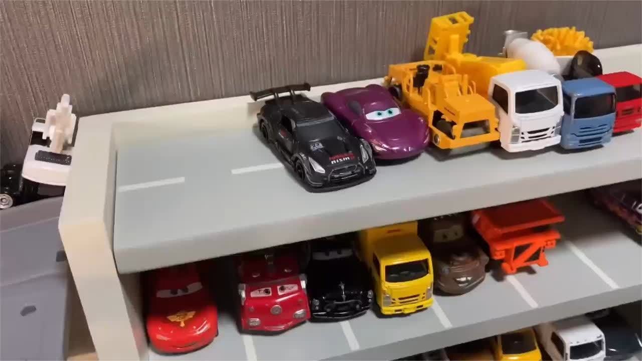 儿童喜欢的赛车总动员玩具车和消防车从旋转轨道滑行进入纸箱