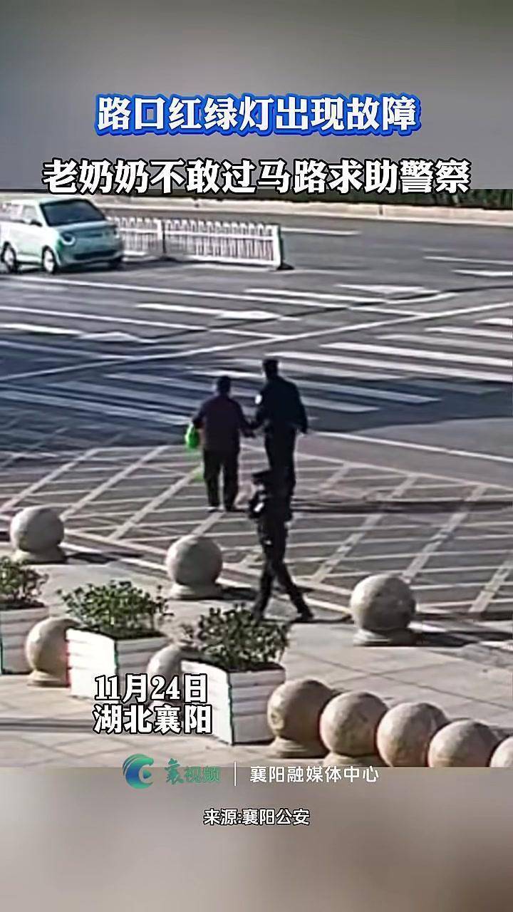 红绿灯出现故障,老奶奶不敢过马路求助警察。(编辑:杨艳群审核:蔡彦燕)
