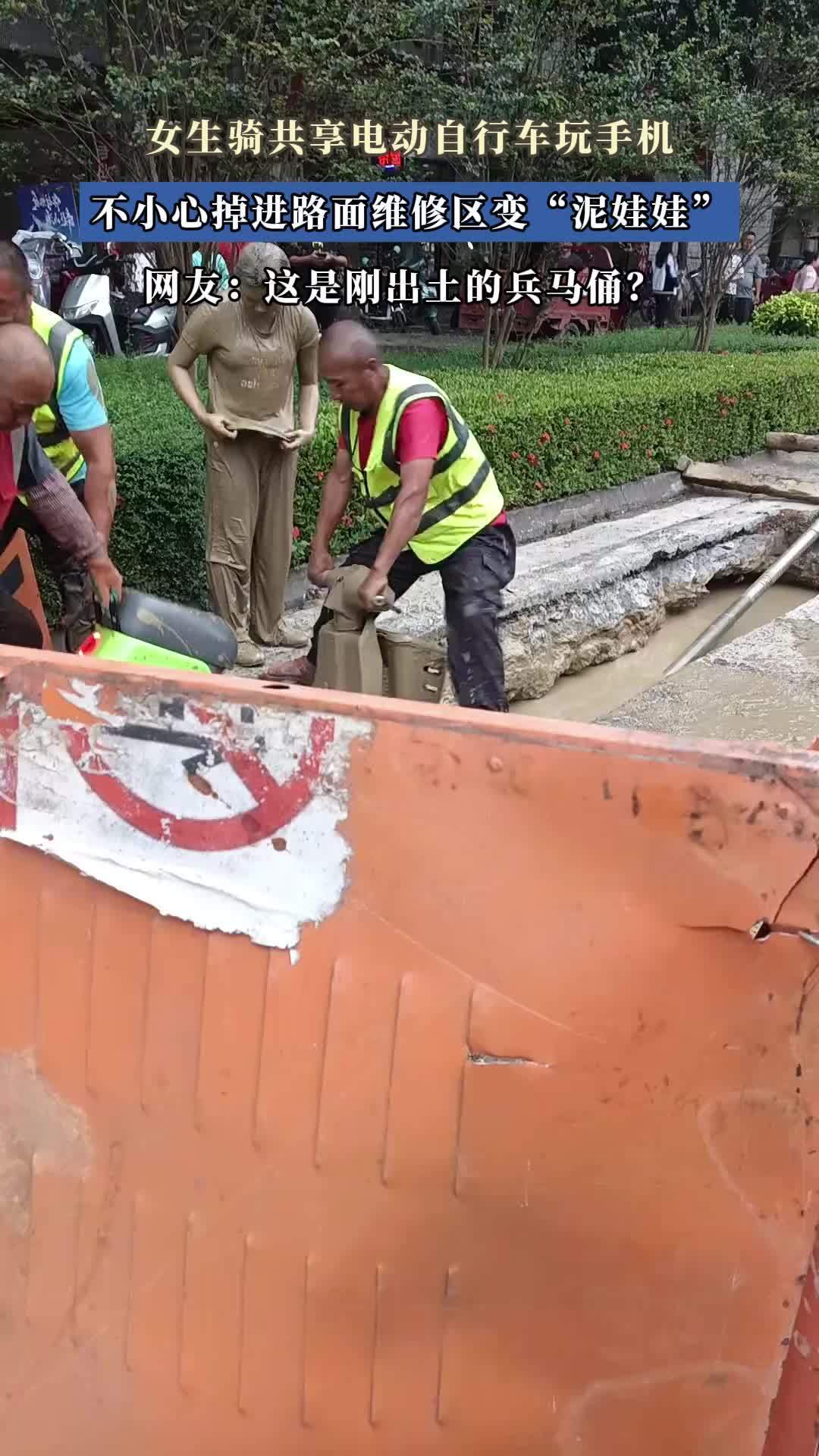 女生骑共享电动自行车玩手机,不小心掉进路面维修区变"泥娃娃"