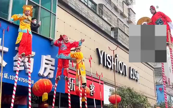 高跷队街上表演引起围观,脚上踩着两根五米长的高跷几十上百斤。...