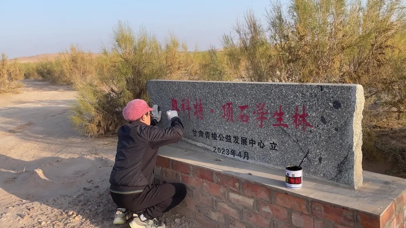 志愿者给褪色的标识牌补上新油漆