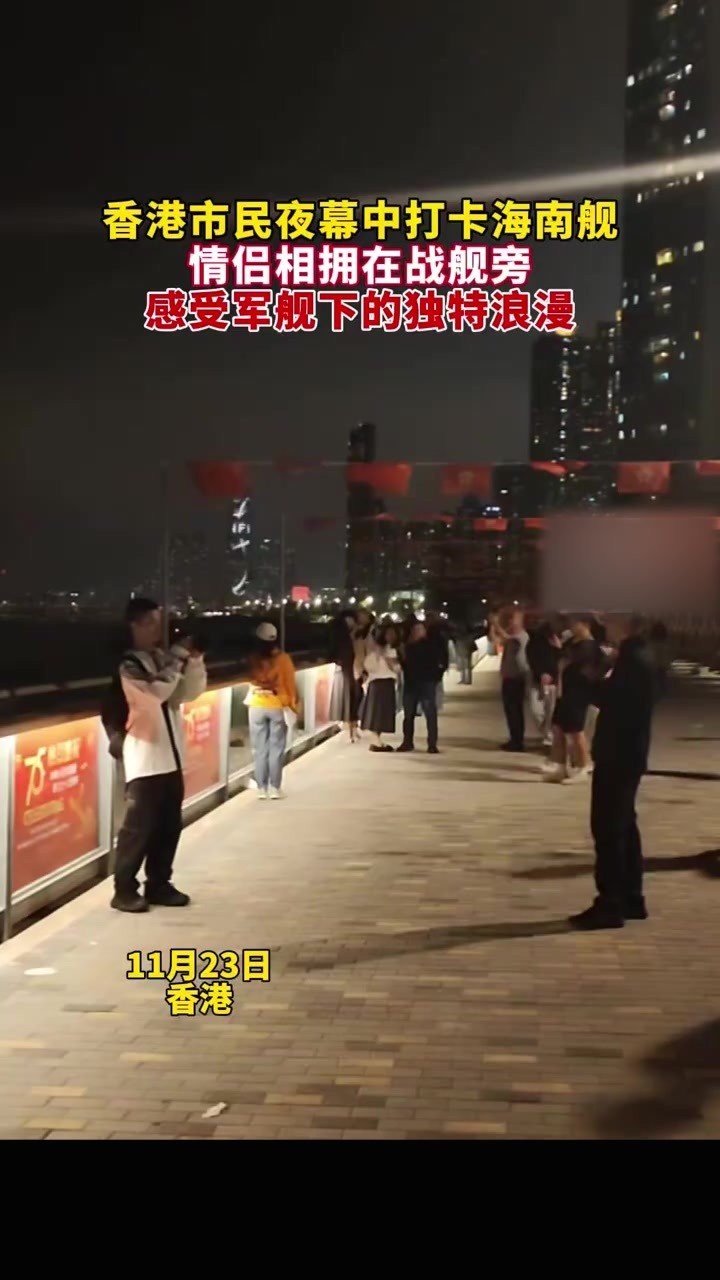 香港市民夜幕中打卡海南舰,不少情侣相拥在战舰旁,感受军舰下的独特...