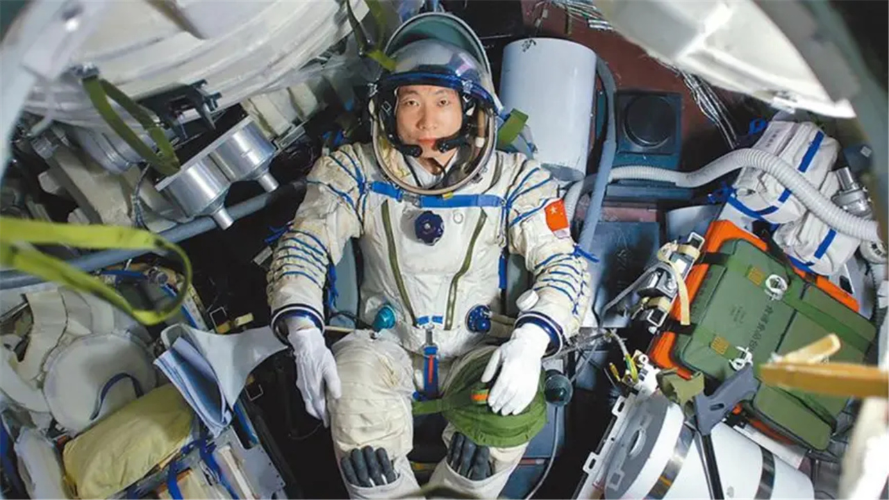 杨利伟步入太空影像在神舟飞船中,向镜头展示两面旗帜