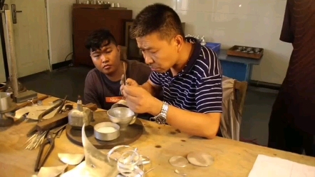 手工锡器制作第七步:一手持本锡裁剪好的锡条,沾石蜡颗粒。右手把...