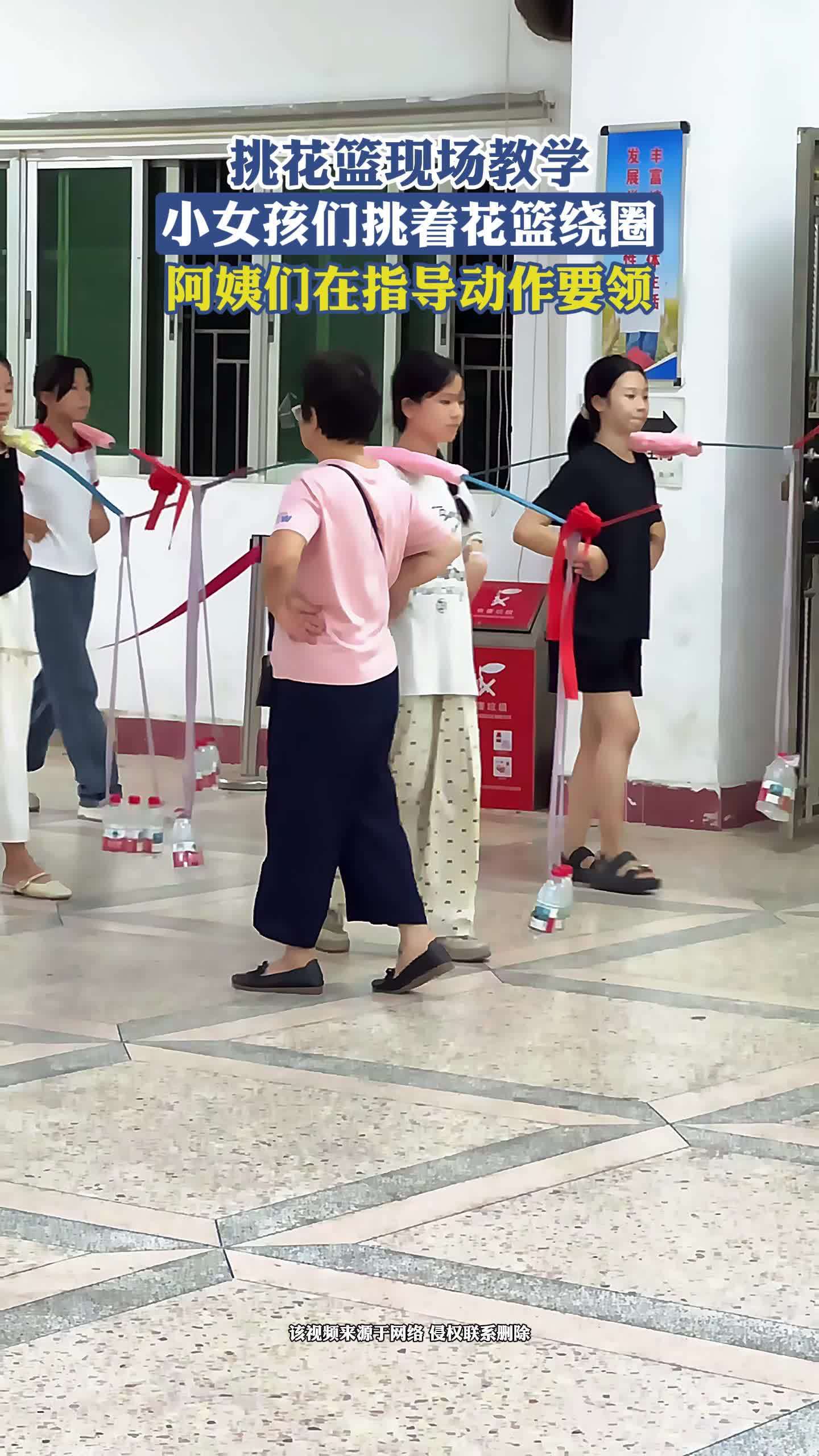 挑花篮现场教学,小女孩们挑着花篮绕圈,阿姨们在指导动作要领