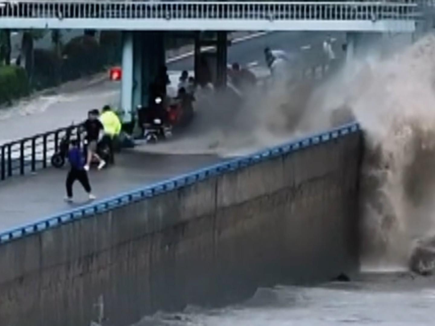 受"普拉桑"影响,钱塘江潮水冲上江岸,路人紧抱栏杆防止被冲走
