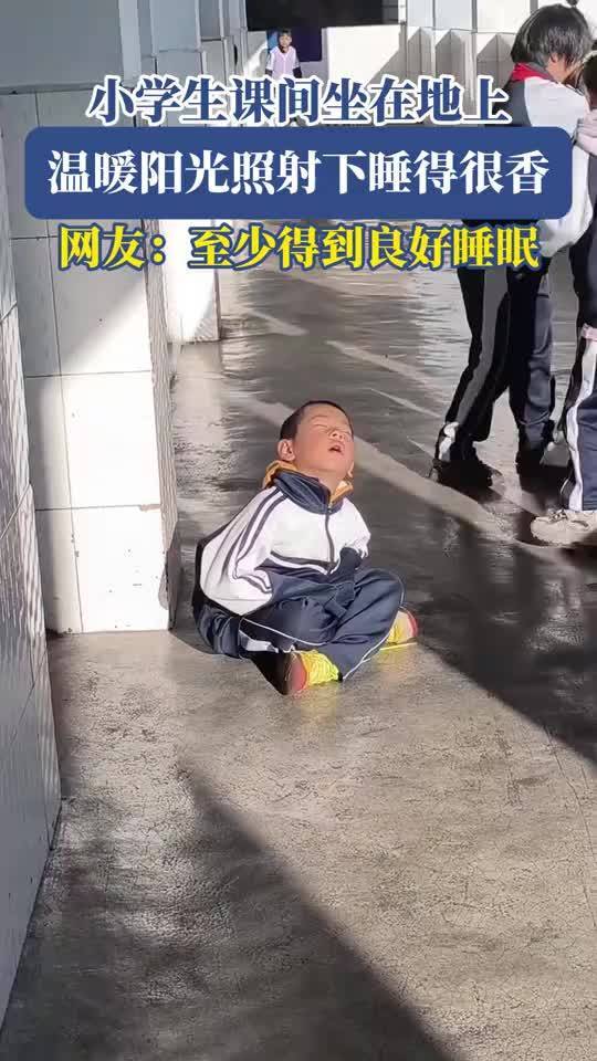 小学生课间坐在地上,温暖阳光照射下睡得很香,至少得到良好睡眠